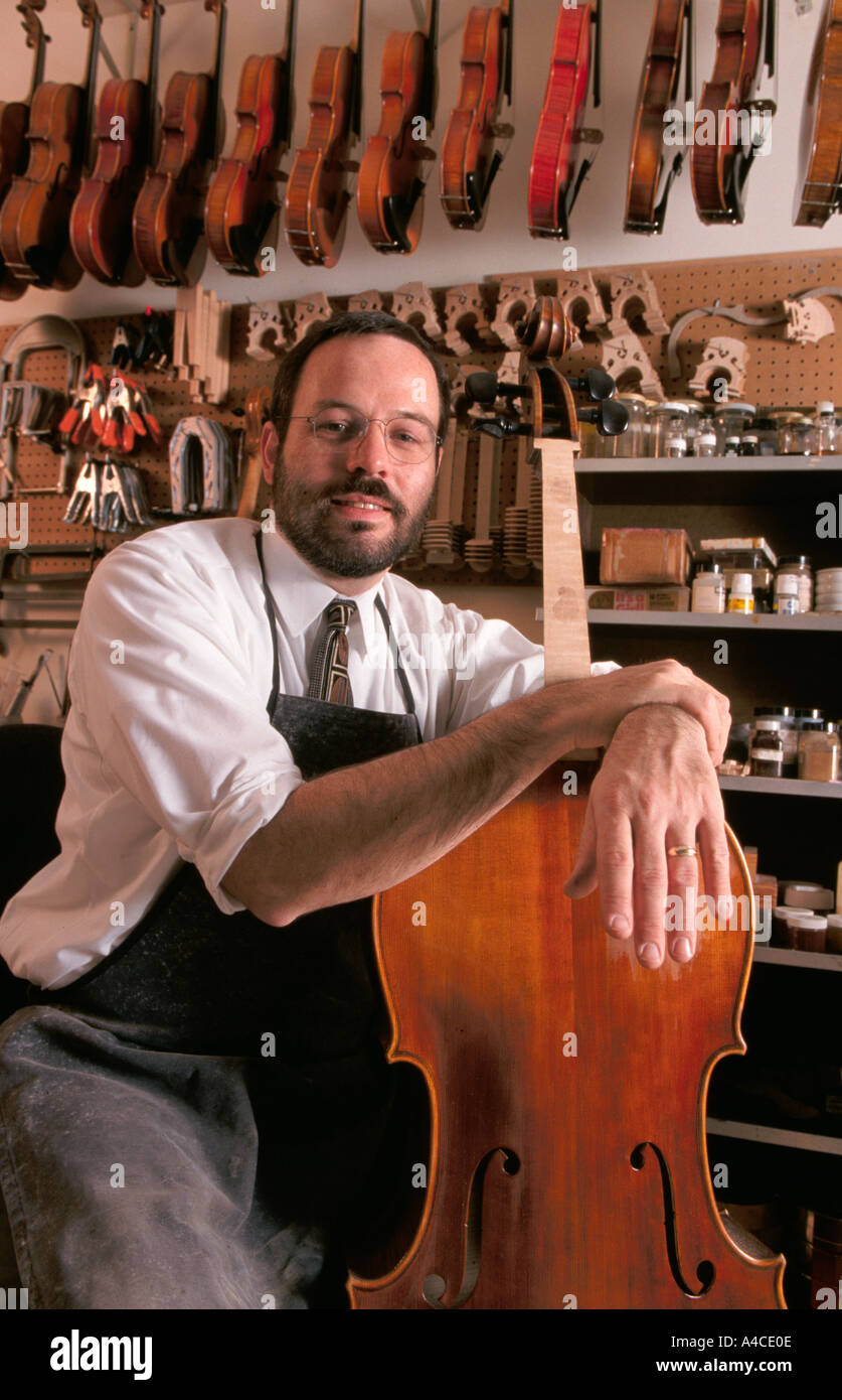 A violin maker poses with a cello under construction in his shop Stock ...