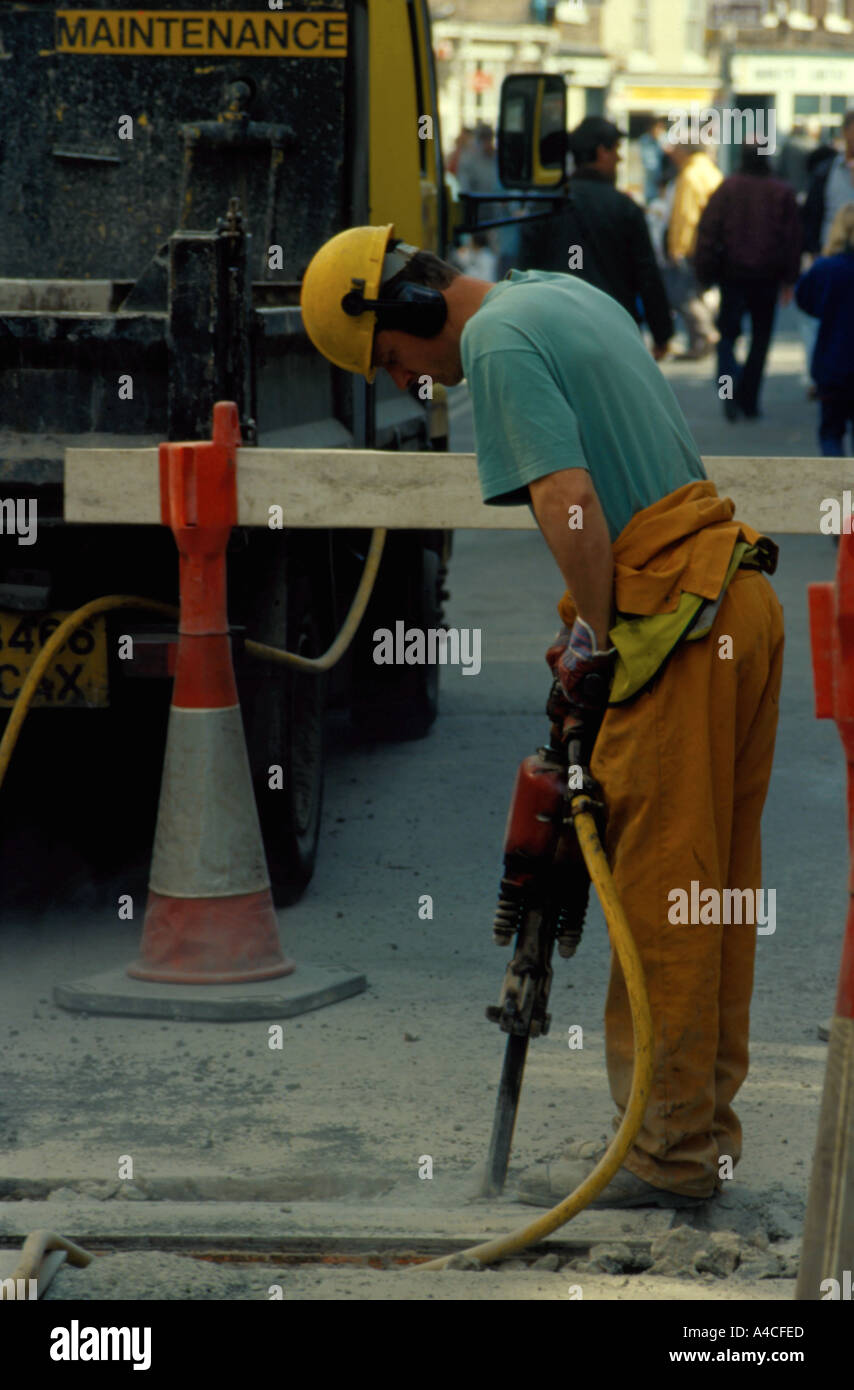 Man using a pneumatic breaker to dig up the road Stock Photo - Alamy