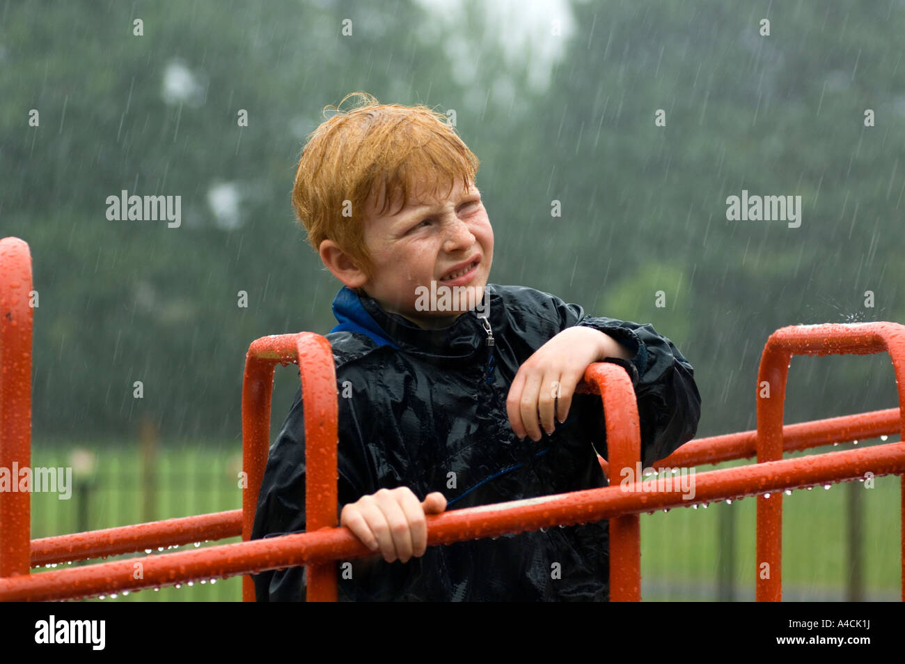 Boy looking unhappy getting wet in a park in the rain Stock Photo - Alamy