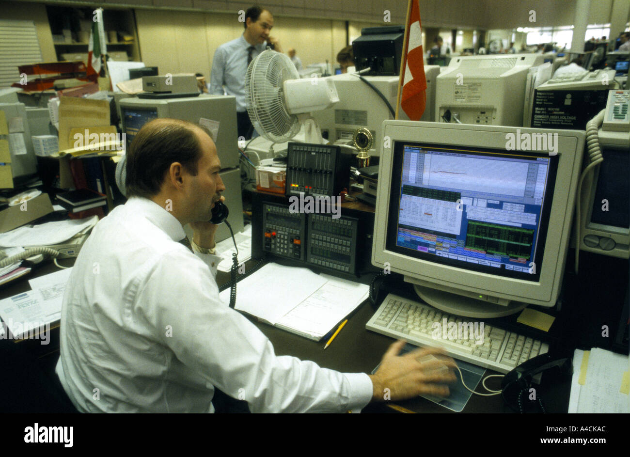 broker in front of computer dealing stocks currency on telephone on a ...