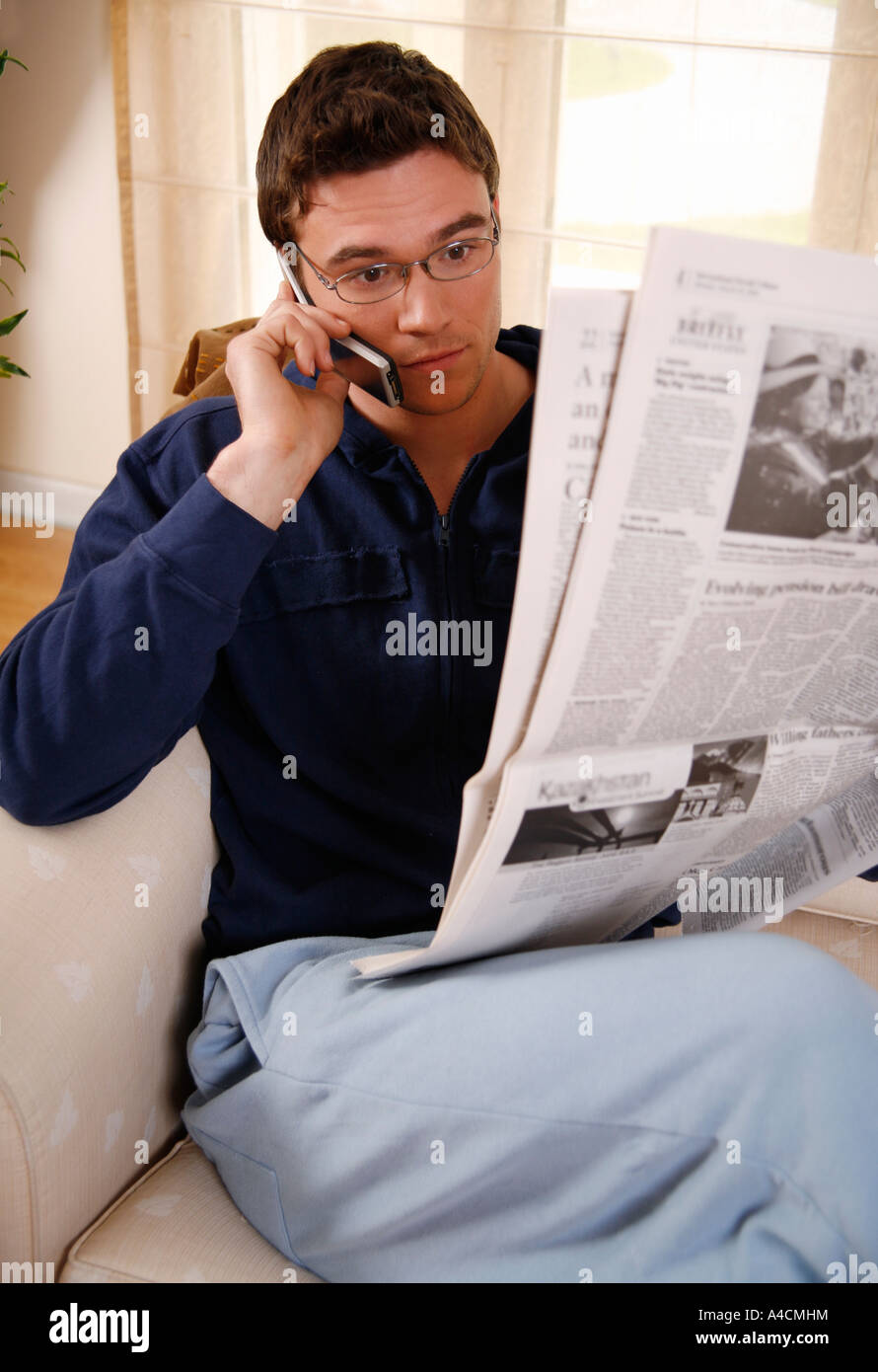 Man reading newspaper and talking on cell phone Stock Photo - Alamy