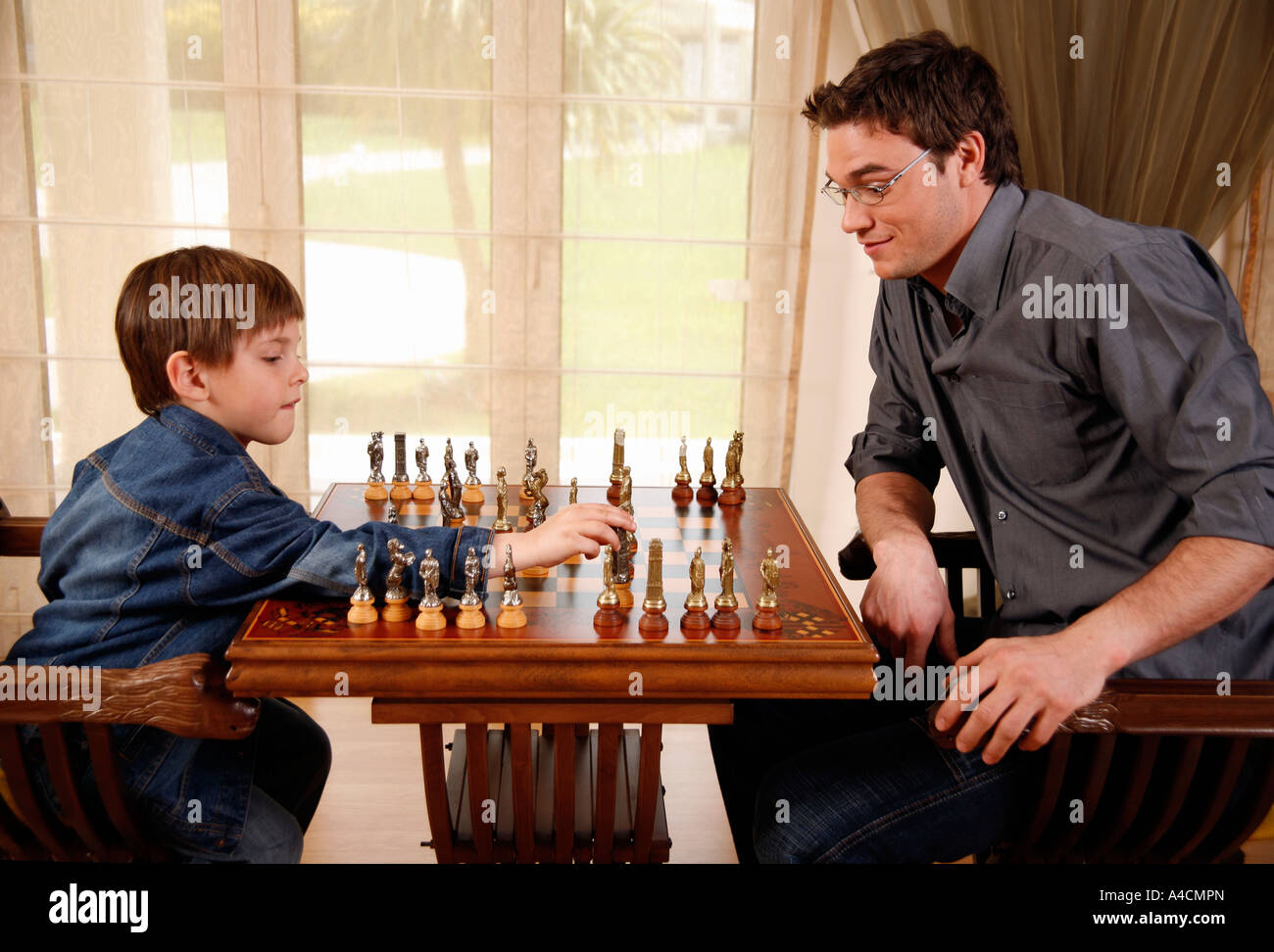 Young man and little boy playing chess Stock Photo - Alamy