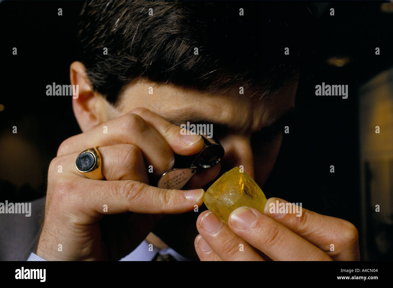Gemologist examining raw diamonds at De Beers, Hatton Garden, london ...