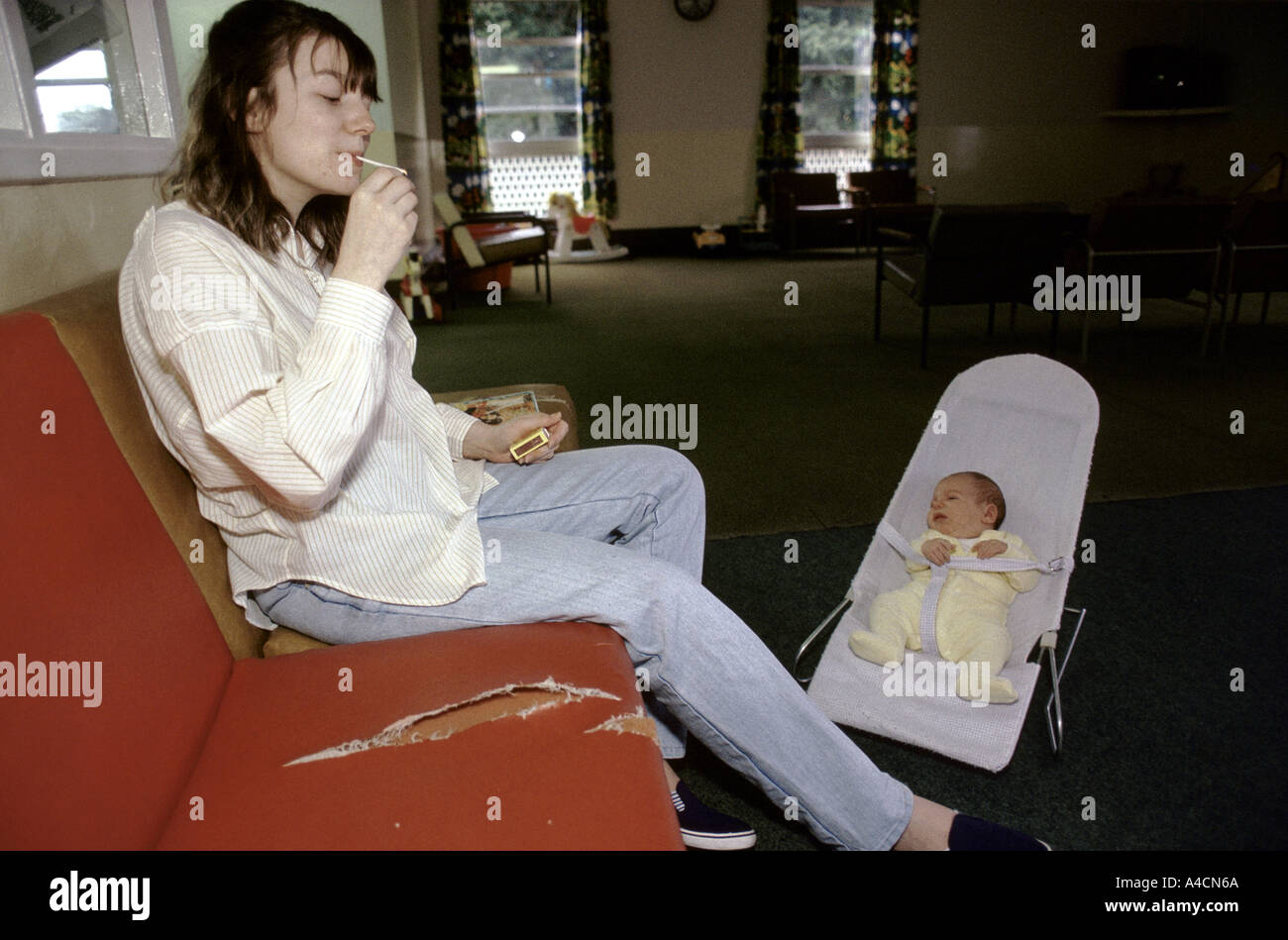 A young inmate lights a cigarette with her sleeping baby close by Stock ...
