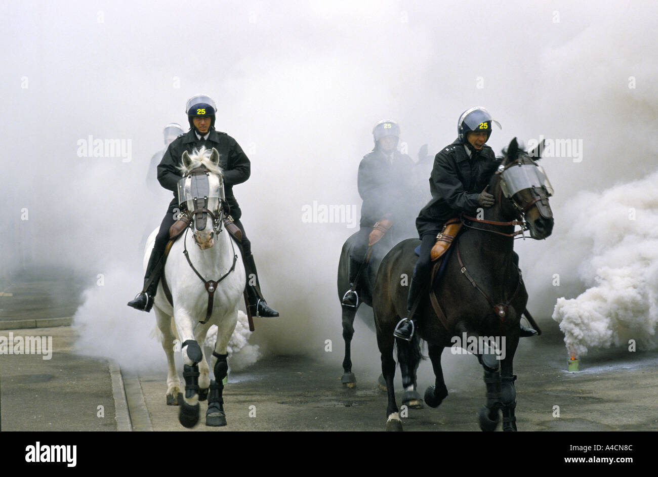 Mounted police ride their horses through smoke flares as part of riot ...