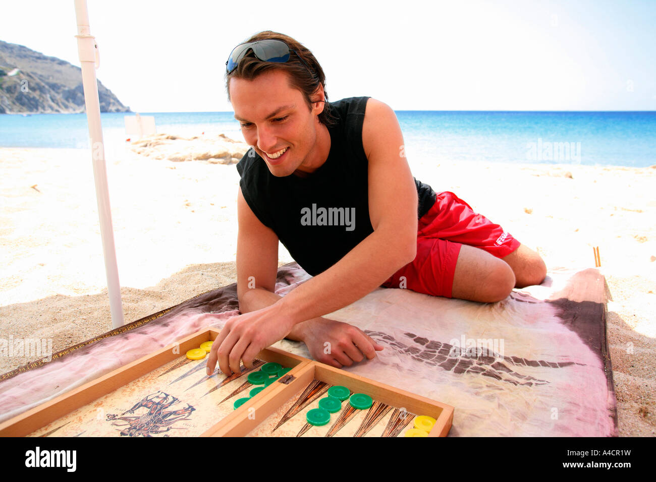 Young man on beach playing backgammon Stock Photo - Alamy