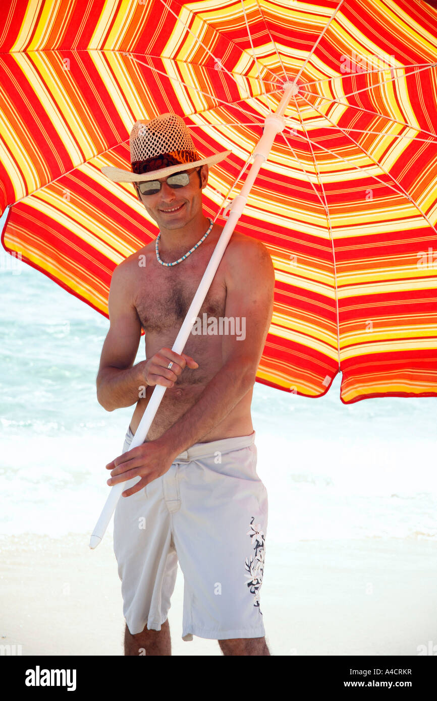 Man on beach with beach umbrella Stock Photo - Alamy