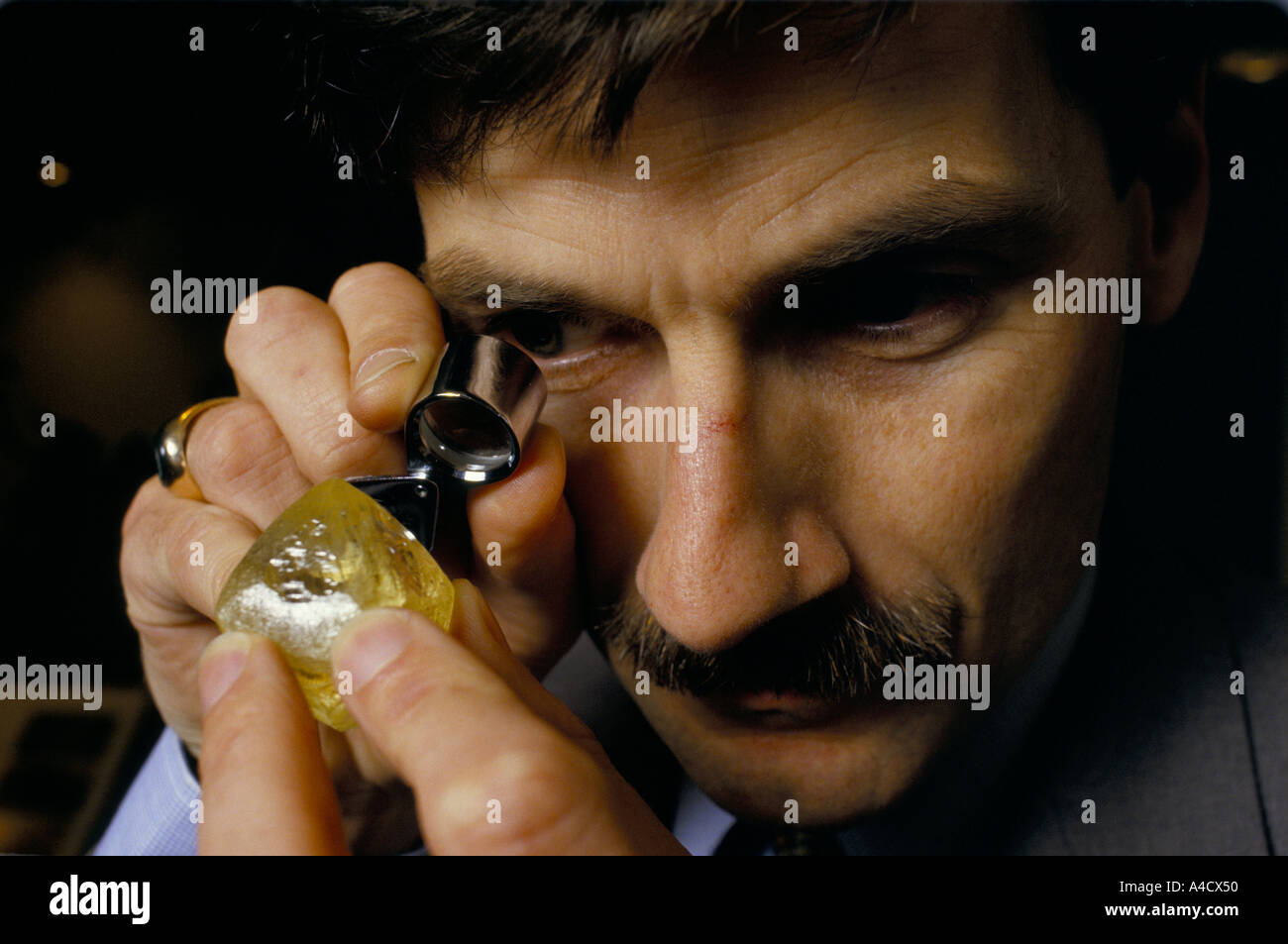 Gemologist examining raw diamonds at De Beers, Hatton Garden, london ...