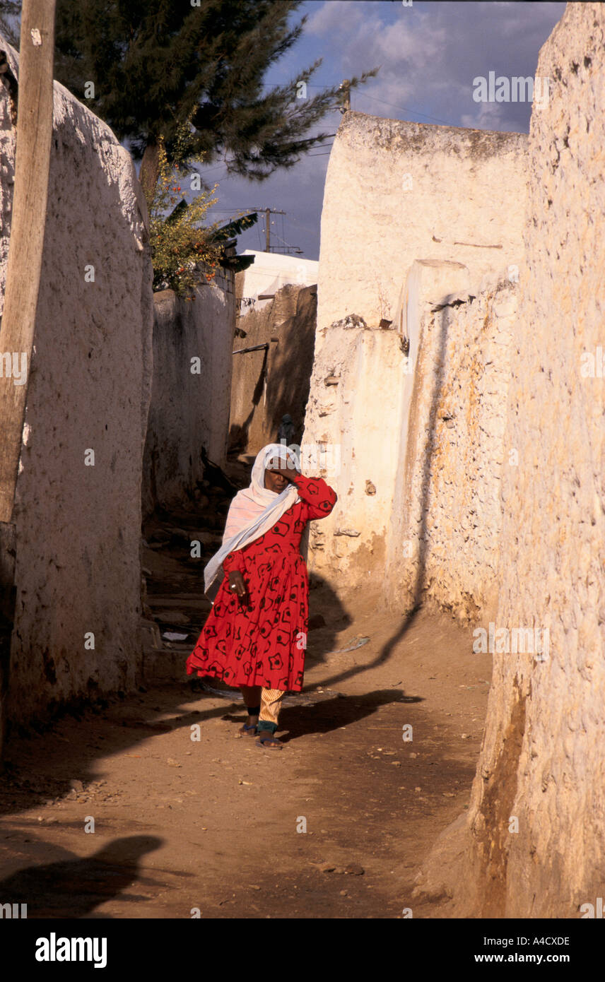 A woman in a red dress walks in the ancient walled city of Harar ...