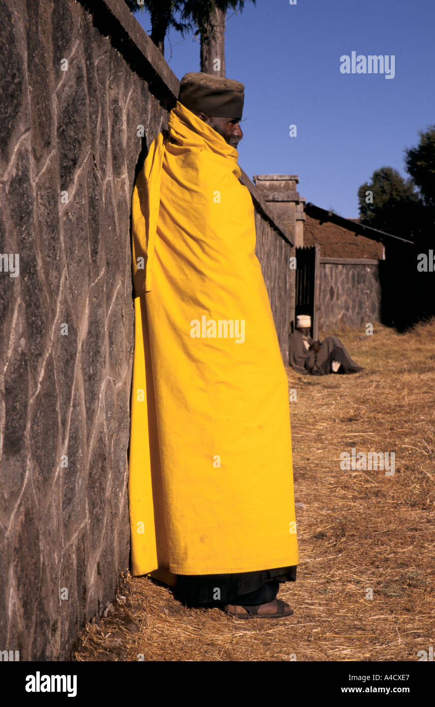 A monk in yellow robes by the wall of the monastery on the extinct ...