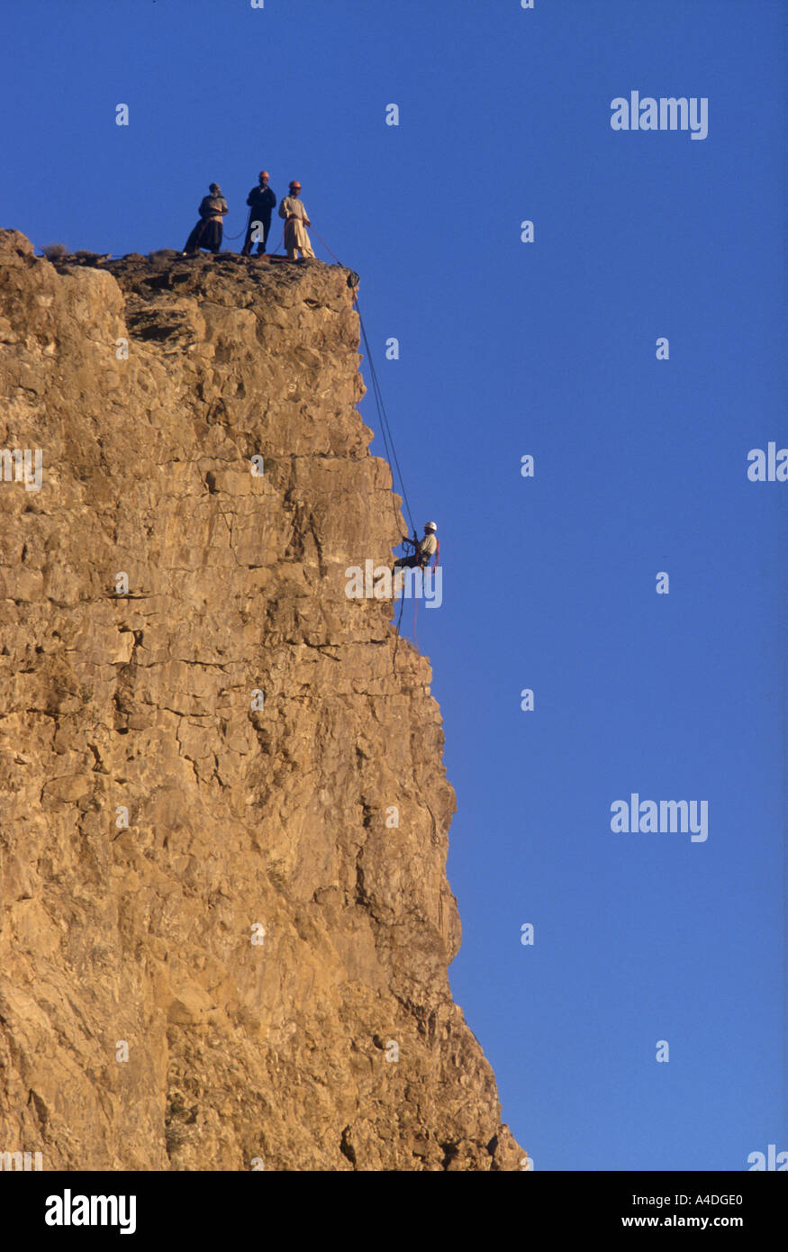 A geologist absails down a cliff face to lay seismic lines surveying ...