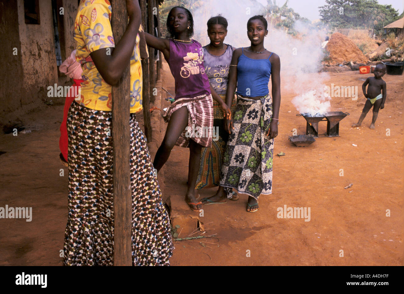 Young women pose whilst village life goes on around them. Bissau ...