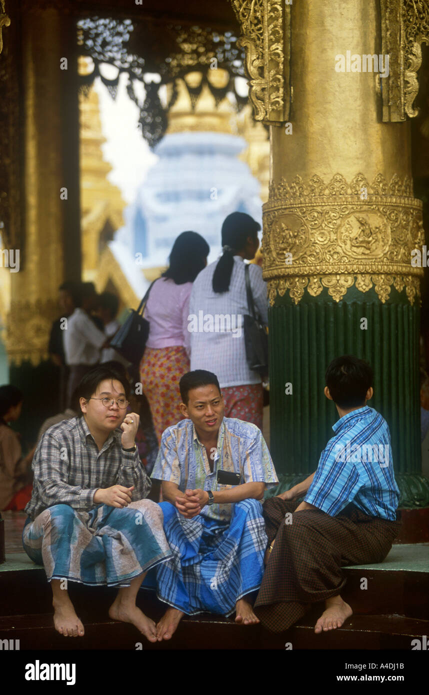 Three young men sitting on the outside steps of Shwedagon Paya Temple ...