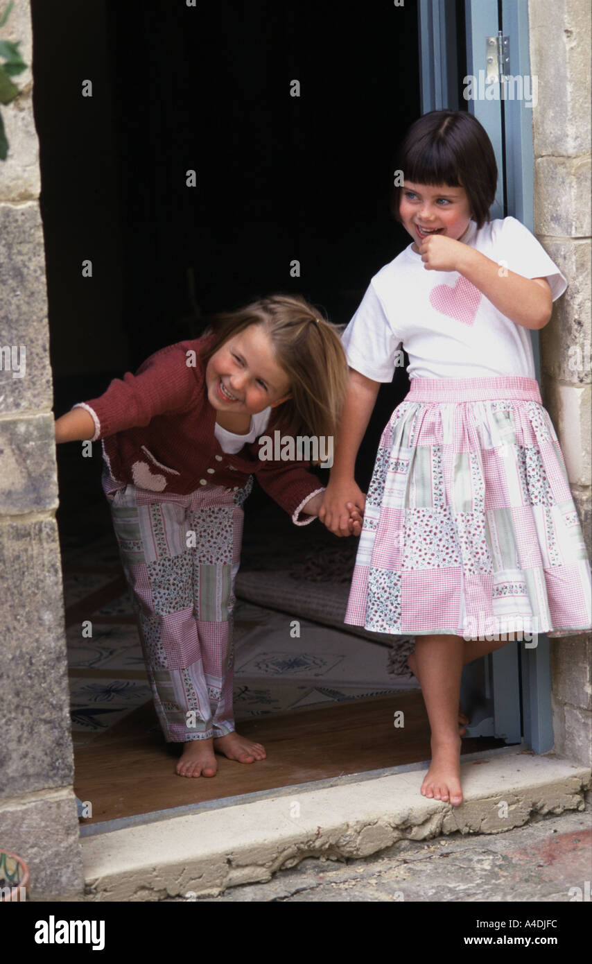 Two girls standing in a doorway holding hands and laughing Stock Photo ...