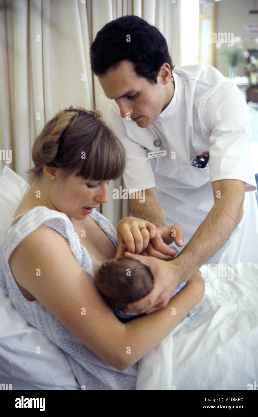 A woman who has just given birth breastfeeding her baby with a male ...