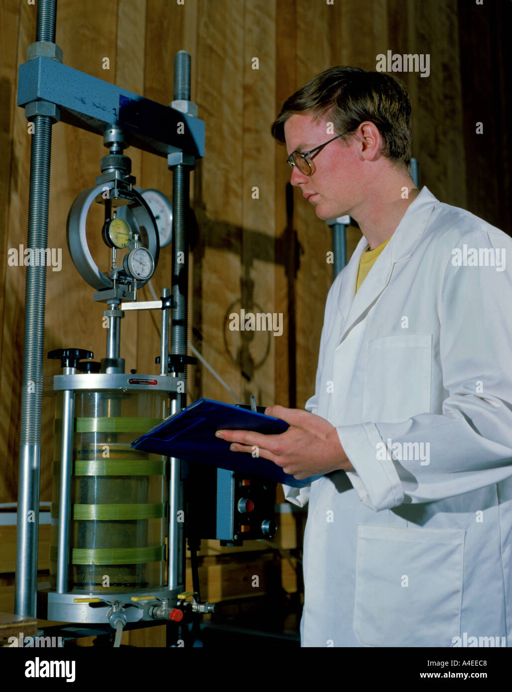 Technician conducting a triaxial compression test on a soil sample ...