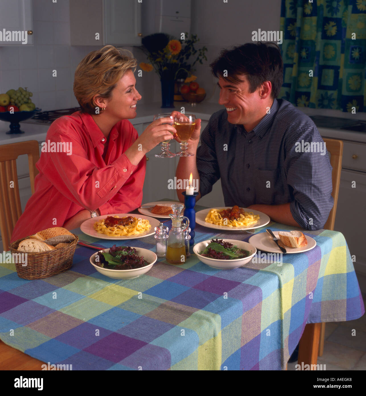 Couple at table having supper. Toasting each other with glass of white ...