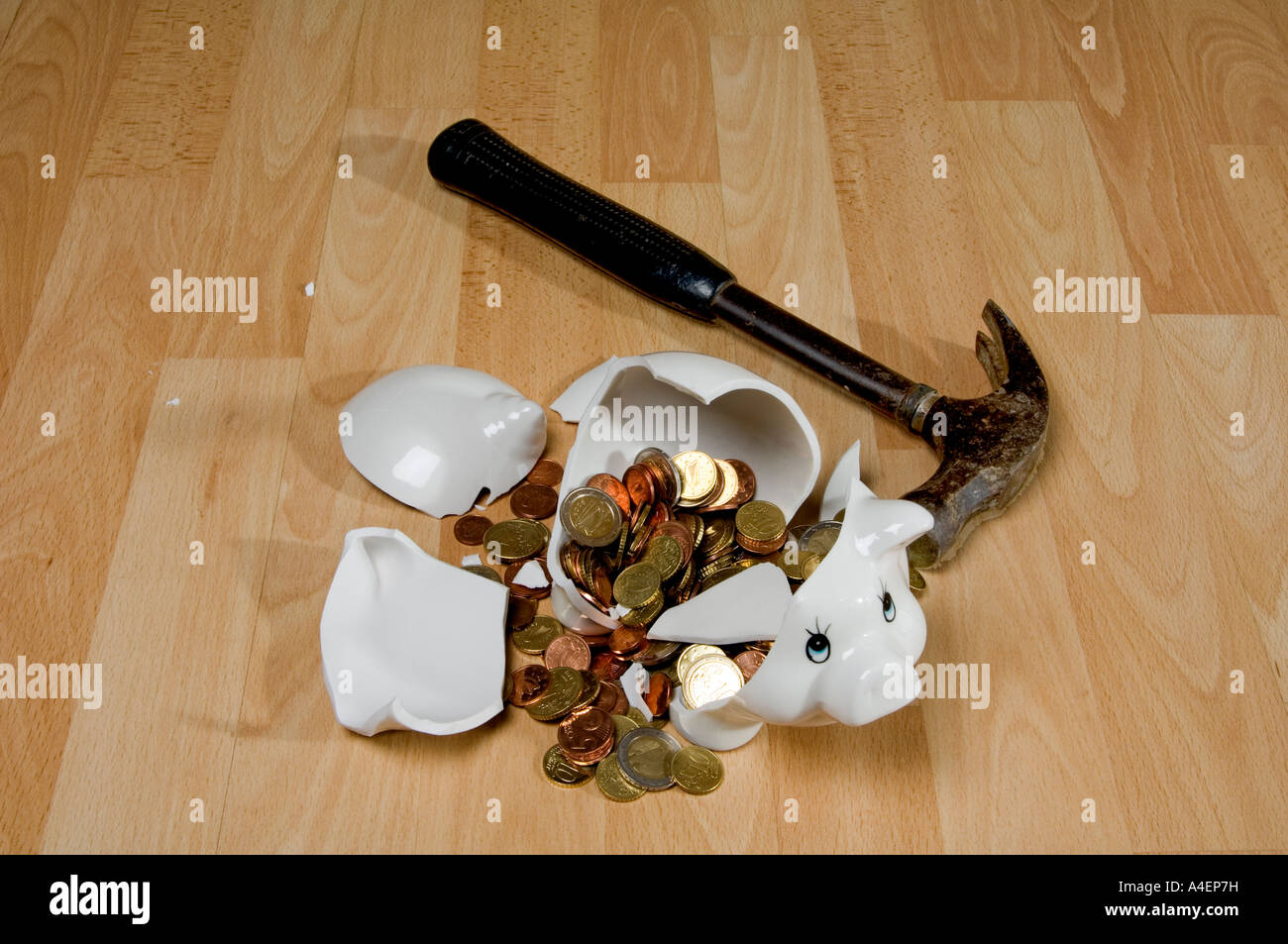 A smashed money piggy bank with coins falling out with the hammer that ...