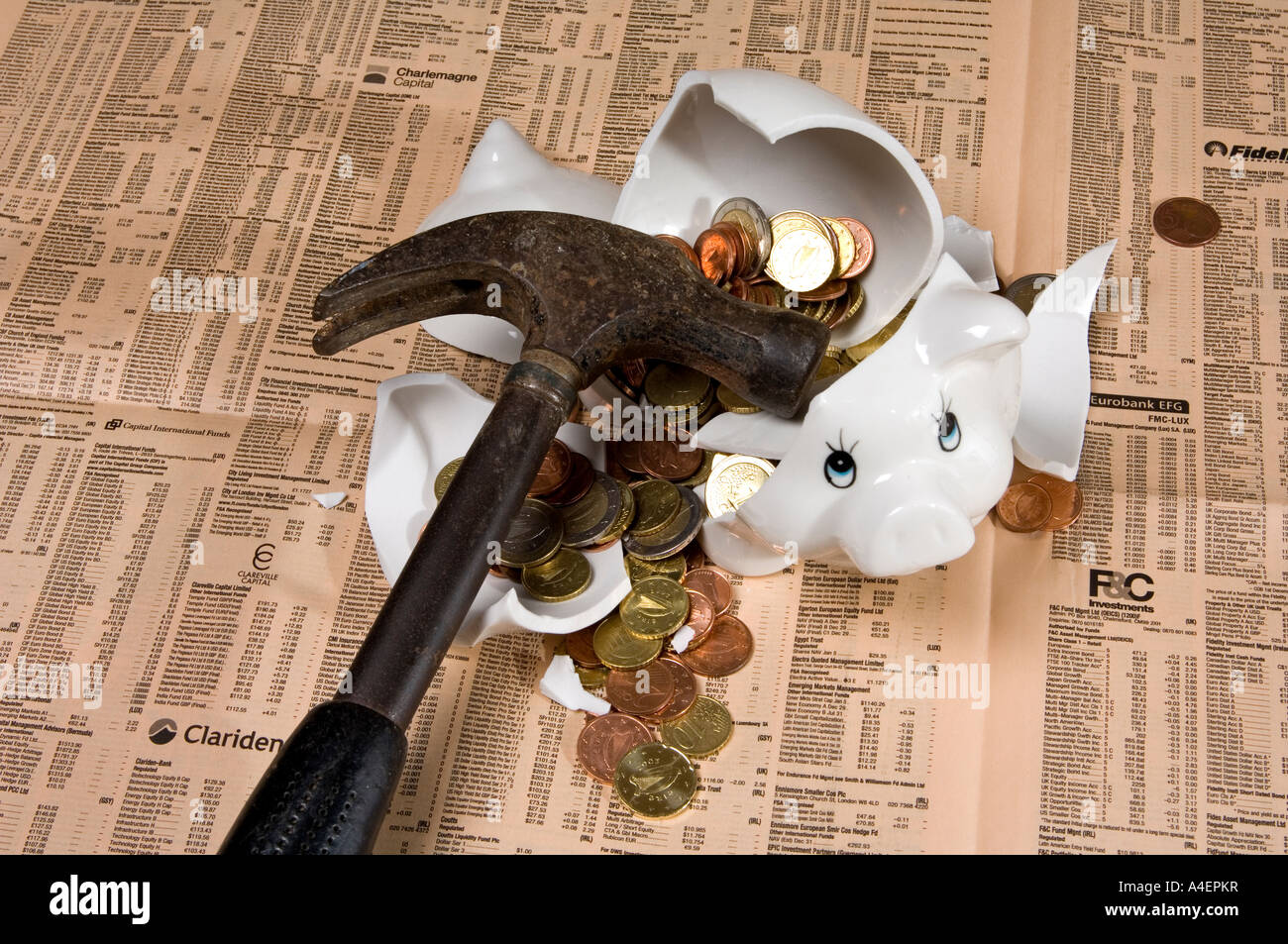 A smashed money piggy bank with coins falling out with the hammer that ...