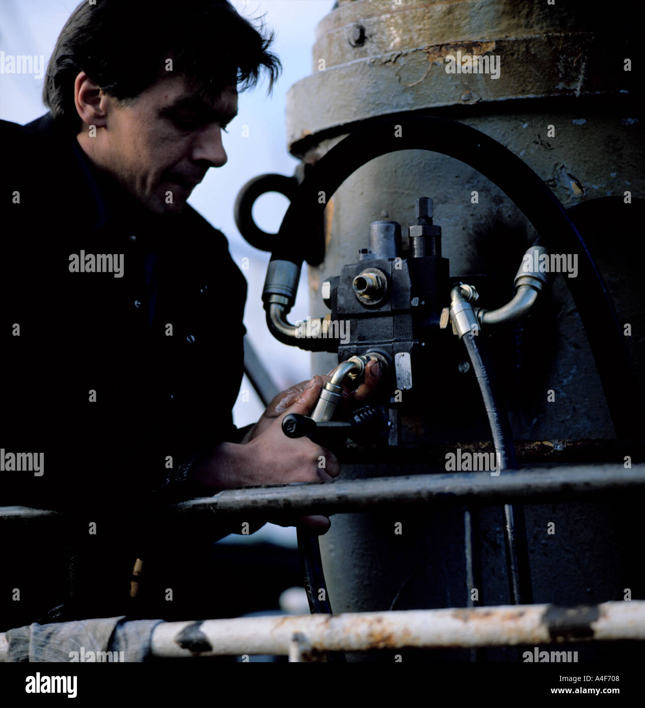 Man fitting hydraulic couplings, ship repair yard, Grimsby, Humberside ...