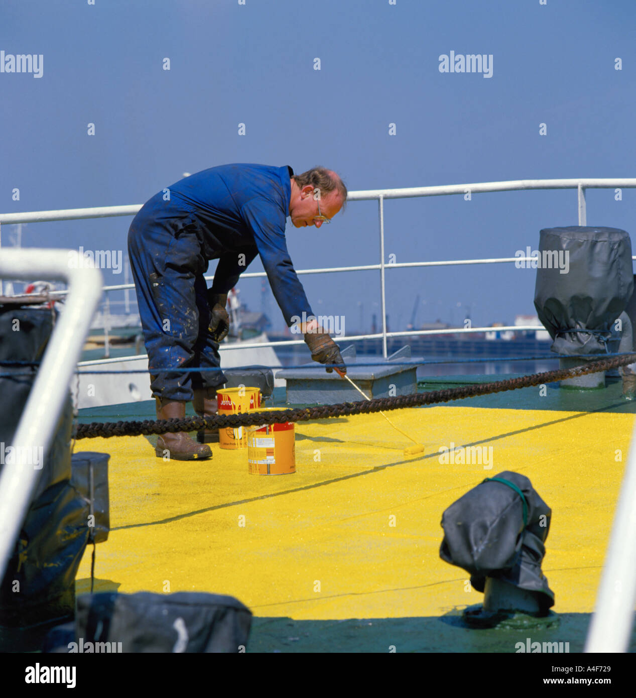 Man painting deck of an oil rig support vessel, Grimsby, Humberside ...