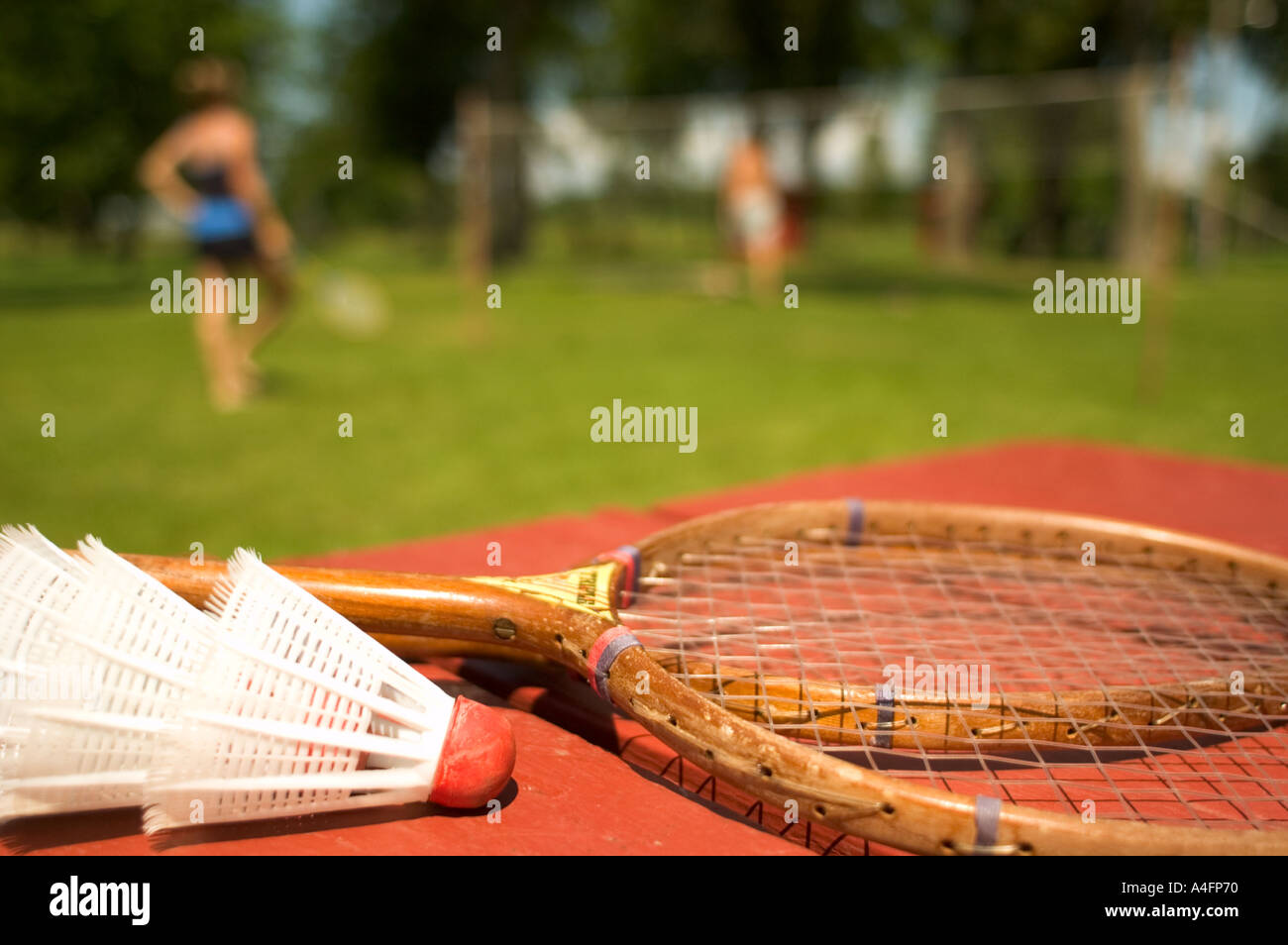 Badminton racquet and shuttlecocks sitting on table with people playing ...
