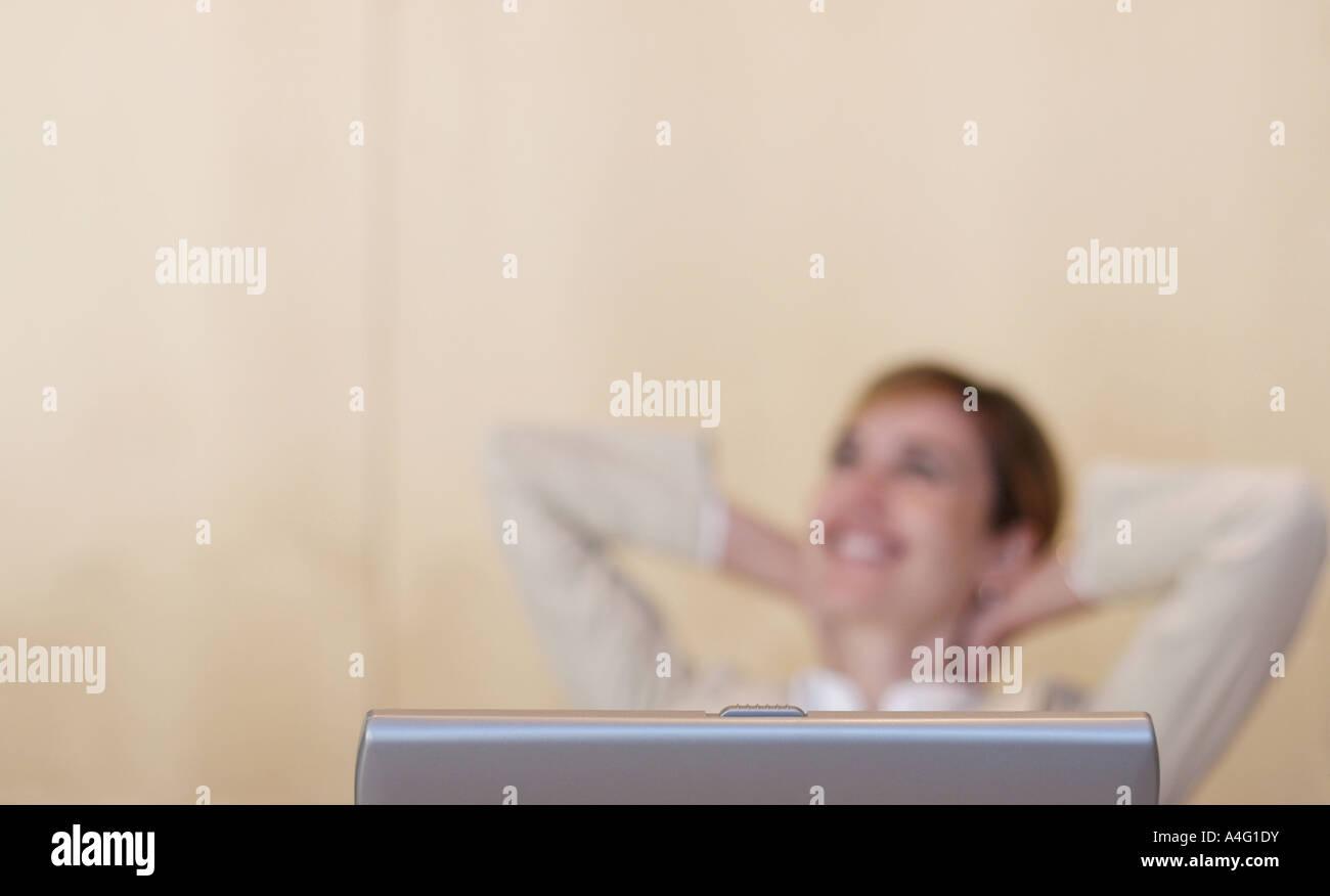 Woman wearing tan jacket is putting both her hands behind her head with ...