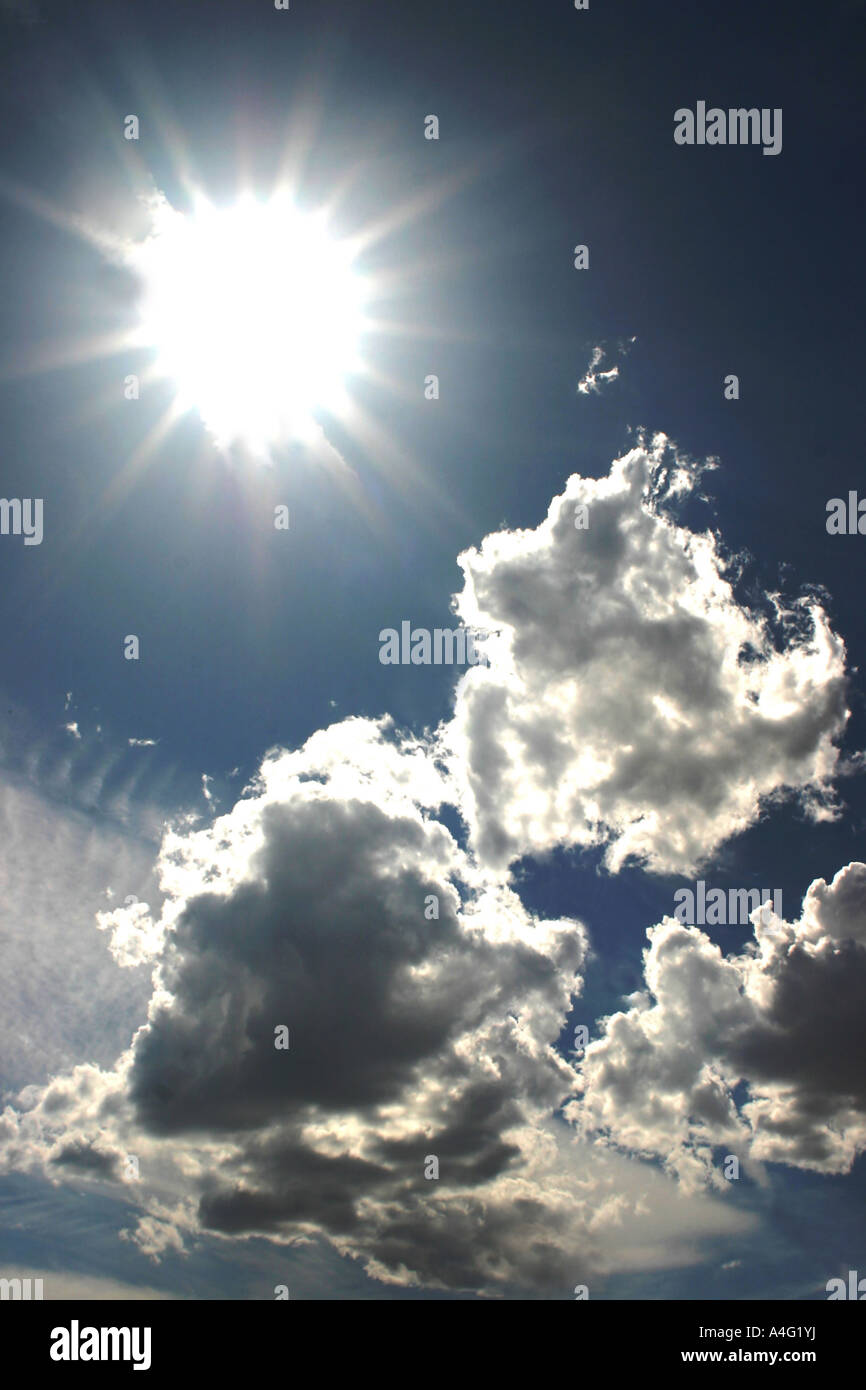 The Sun s rays shines through the clouds in a blue sky Stock Photo - Alamy