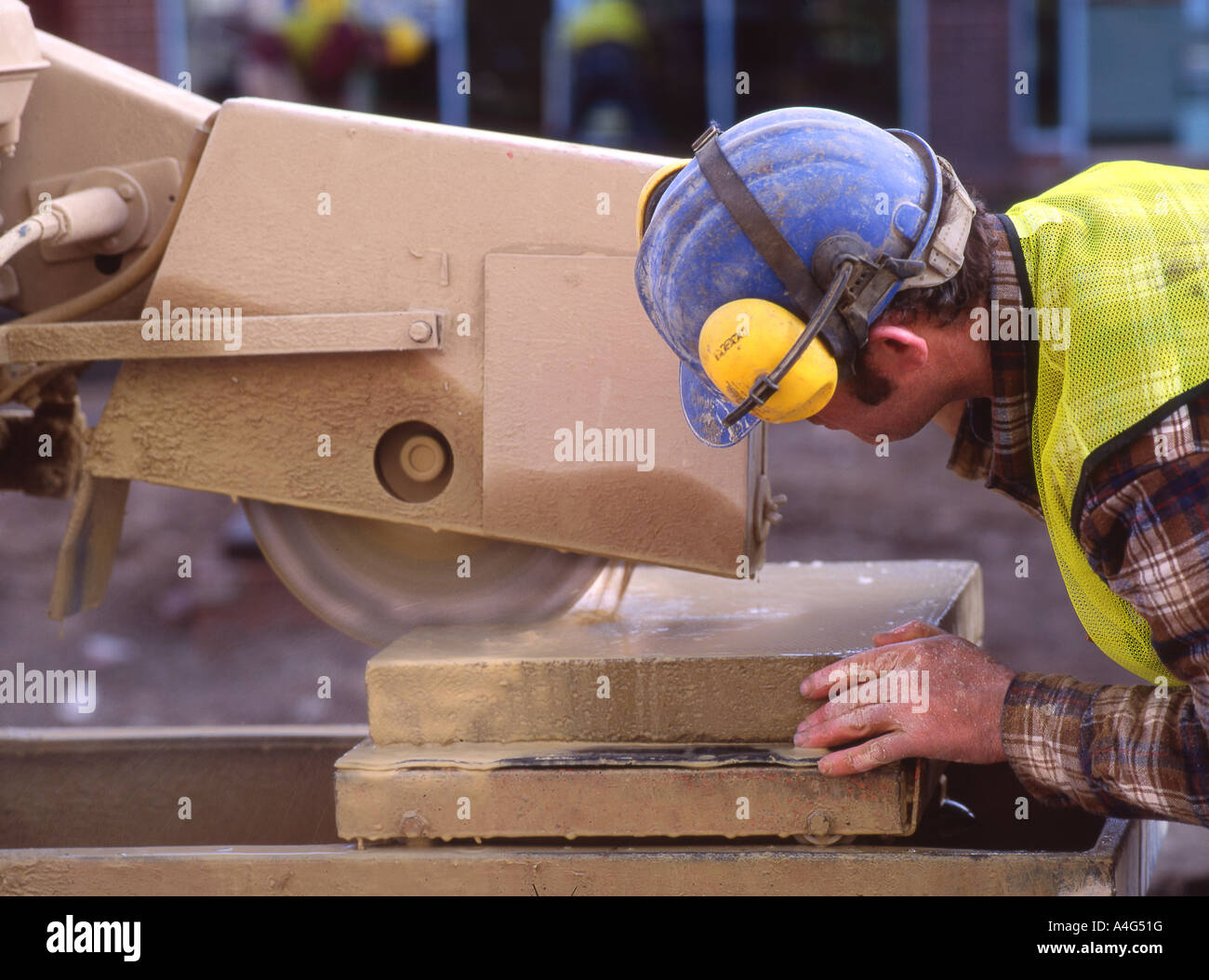 Worker using high speed diamond cutting wheel to cut stone material ...