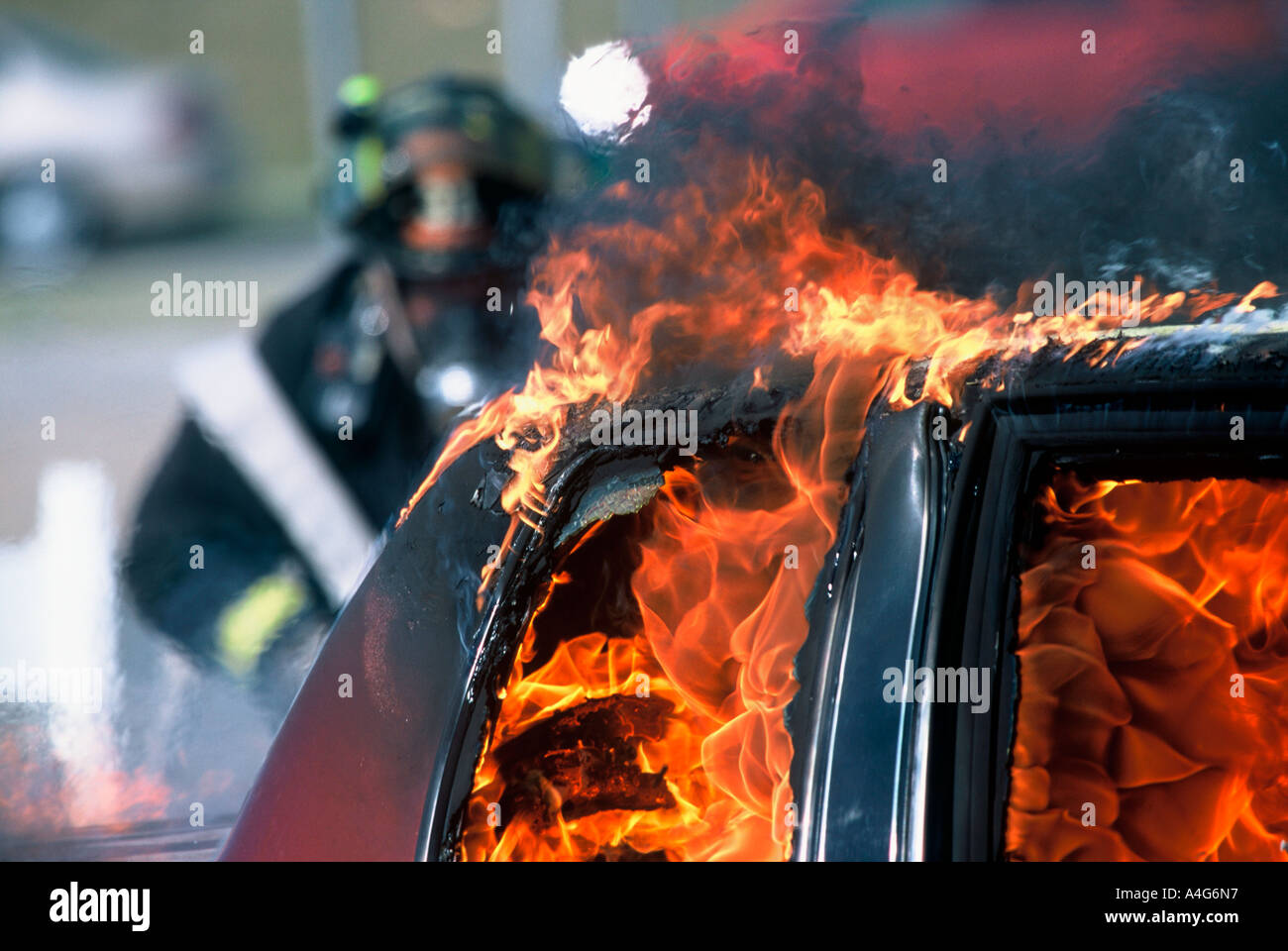 A firefighter with a hose walking around a car fire Stock Photo - Alamy
