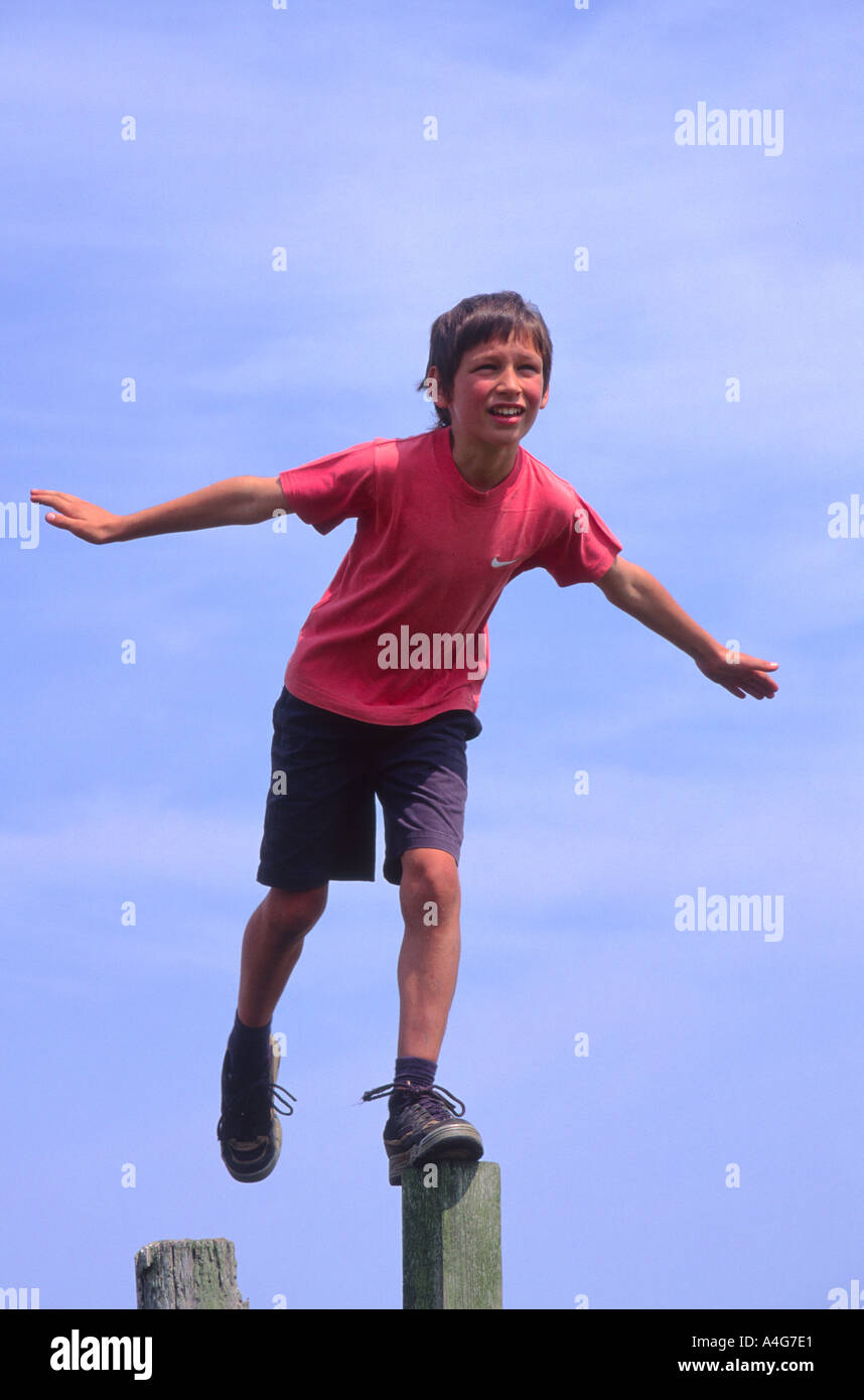 Boy balancing on one leg on a fence post Stock Photo - Alamy