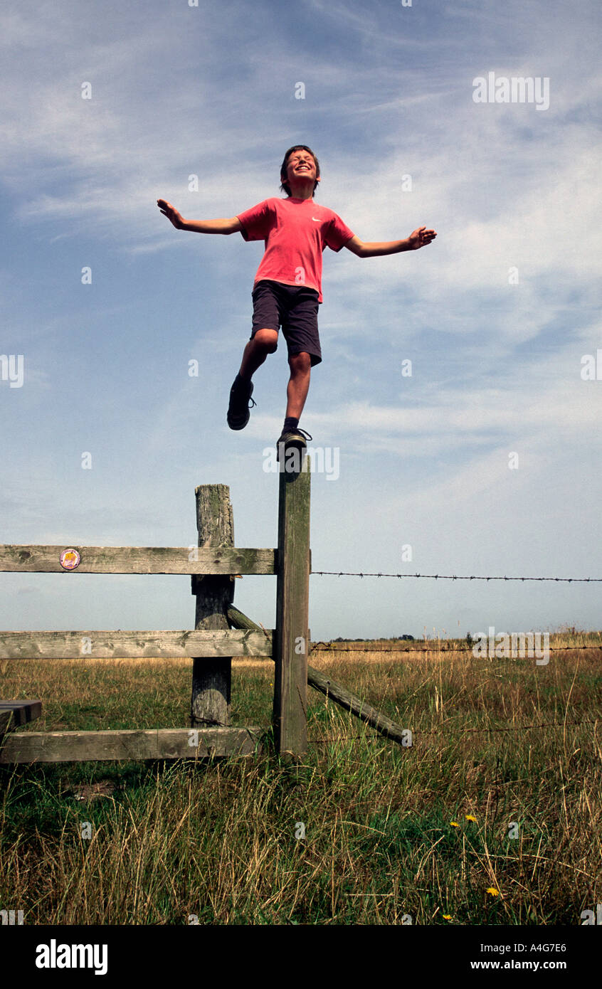 Boy balancing on one leg on a fence post Stock Photo - Alamy