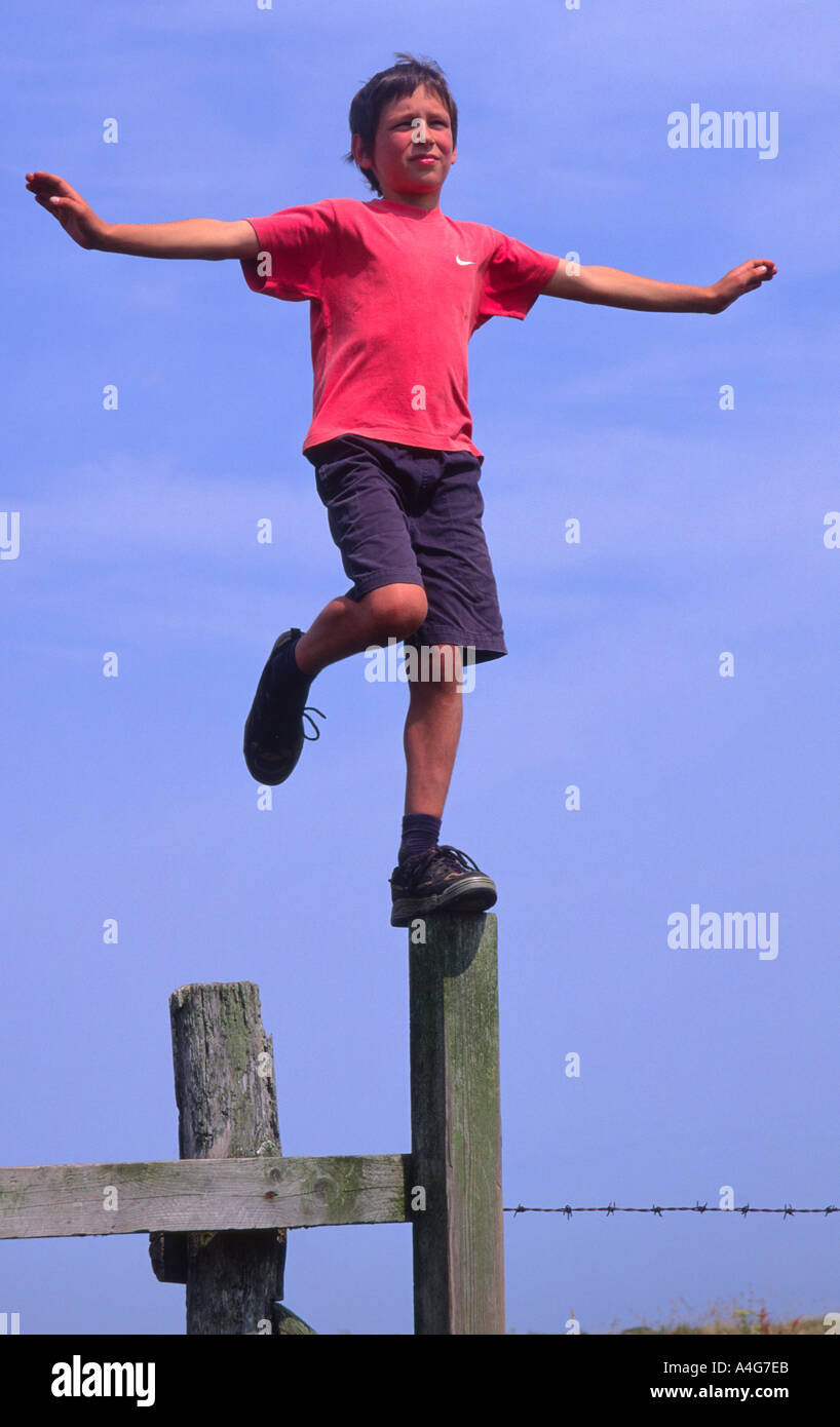 Boy balancing on a fence post Stock Photo - Alamy