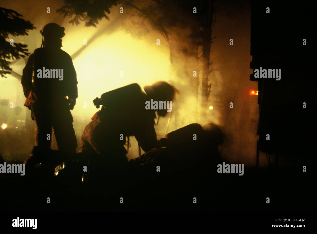 One fire fighter standing one fire fighter bending over and one fire ...