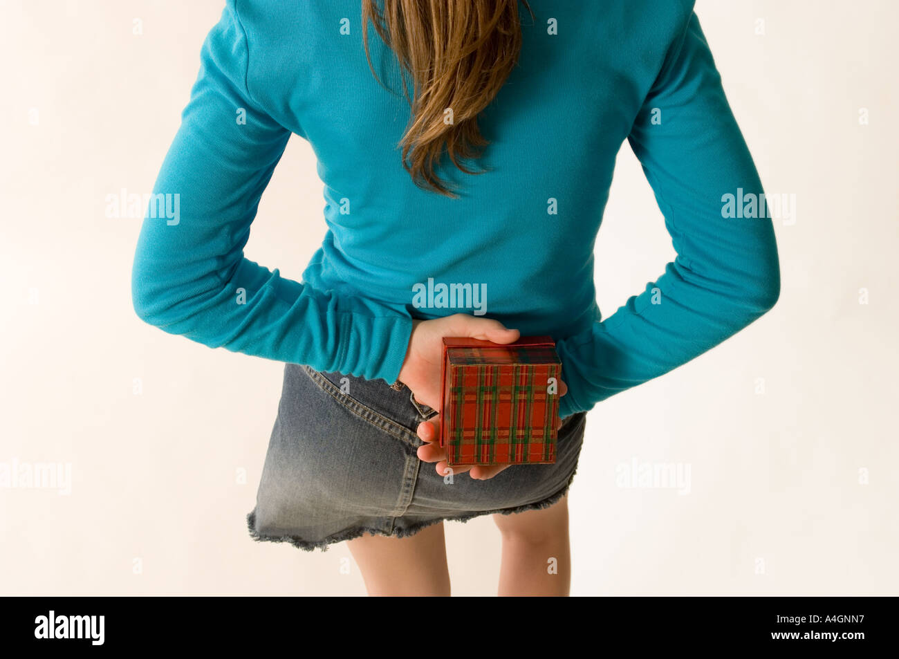 Girl hiding present behind her back Stock Photo - Alamy