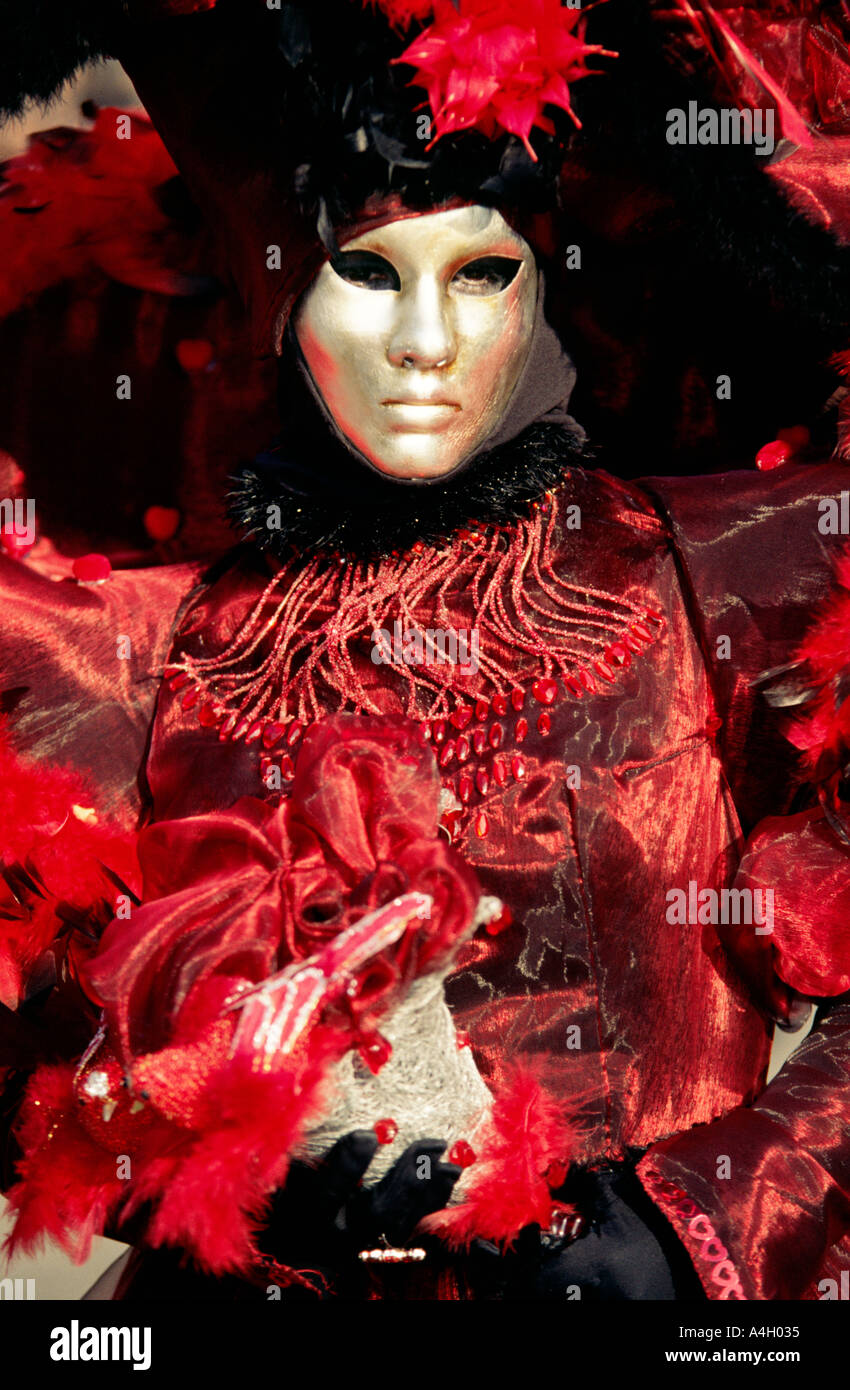 Portrait person in a white mask dressed in a rich red and black cloth ...