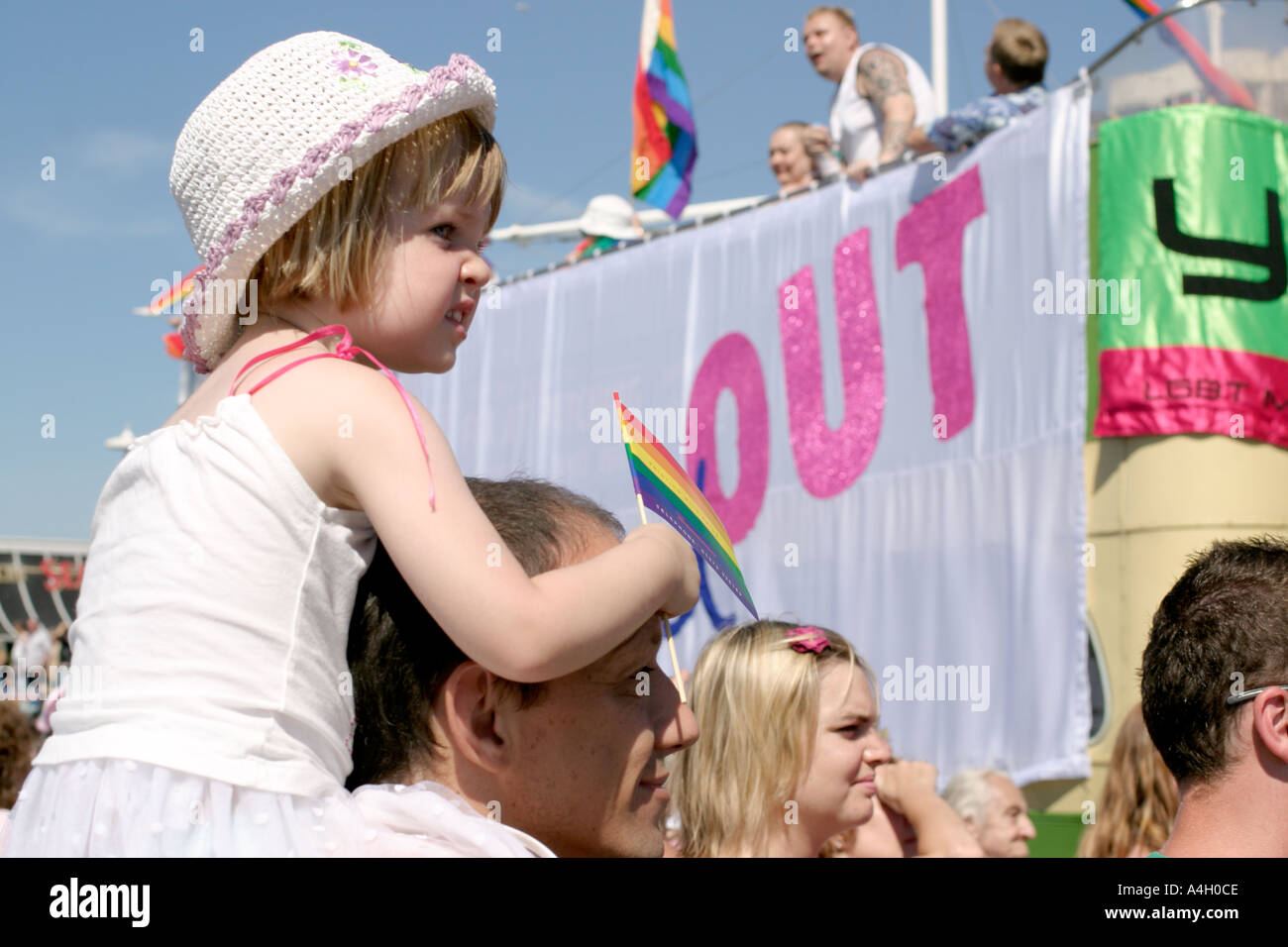 Child seated on fathers shoulders watching passing Gay Pride parade ...