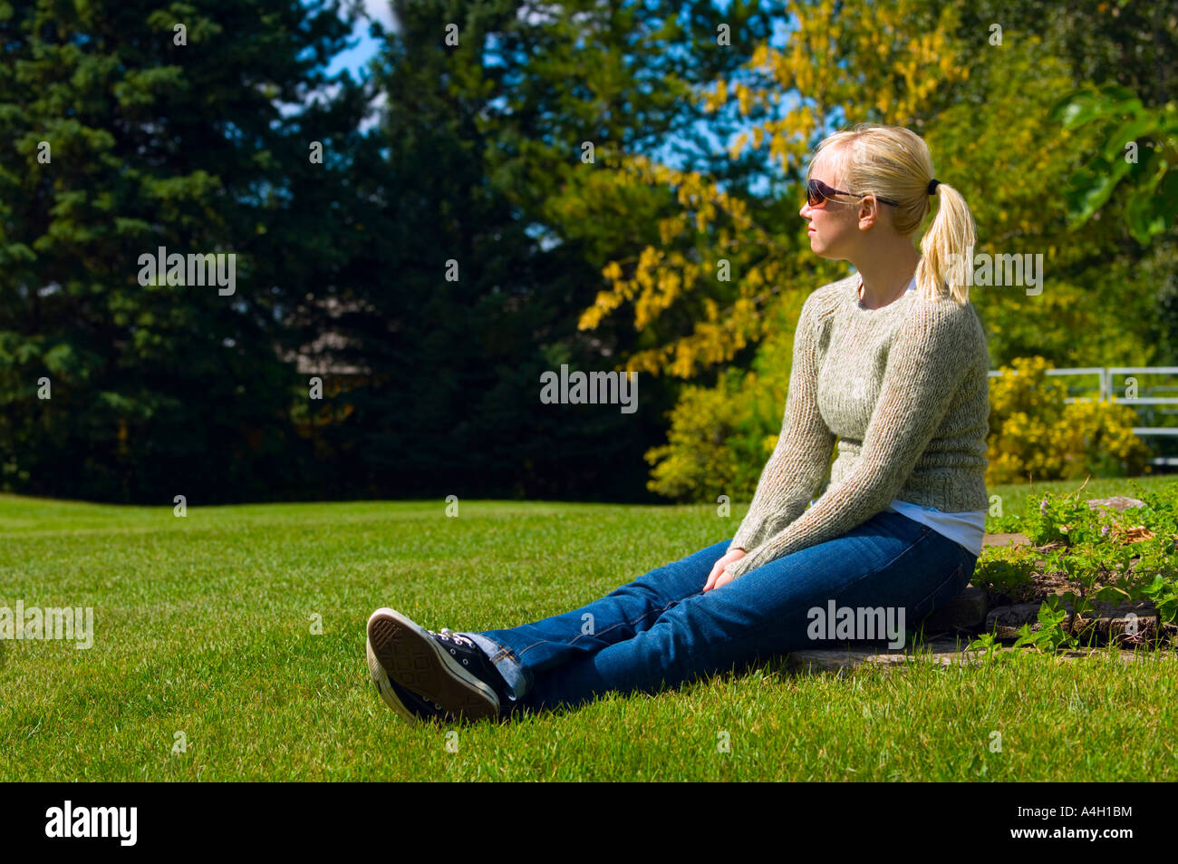 Young woman sitting in the grass Stock Photo - Alamy