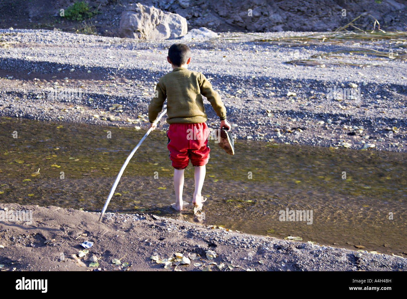 CHINA SIMATAI Young Chinese boy wading across a stream in the rural ...