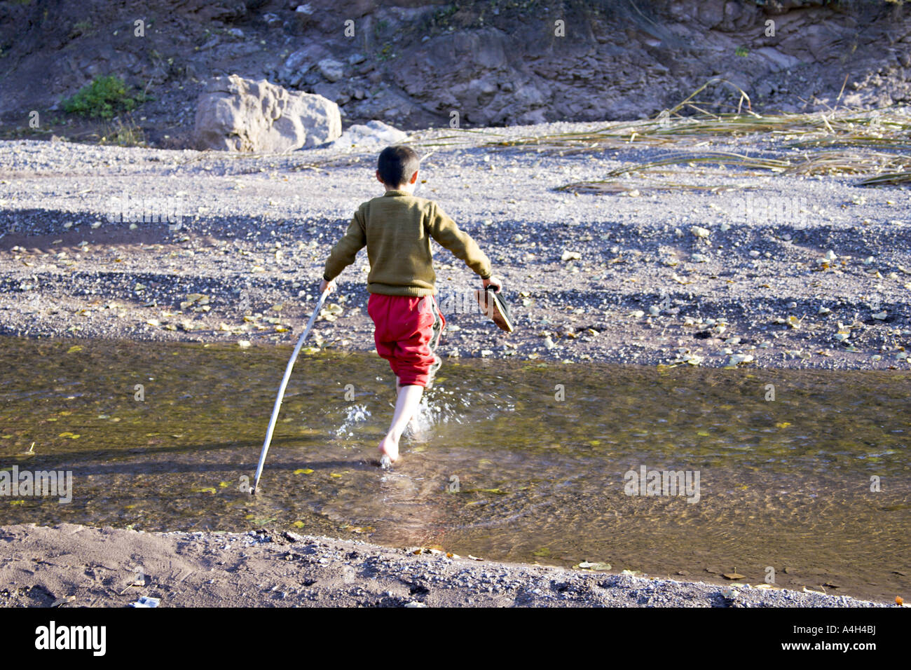CHINA SIMATAI Young Chinese boy wading across a stream in the rural ...