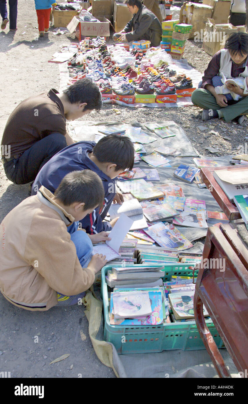 CHINA BEIJING Young Chinese boys reading books for sale at a open air ...