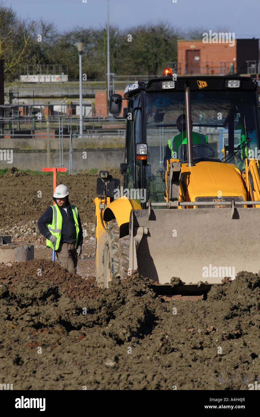 Construction site mechanical digger bulldozer and workmen in safety ...