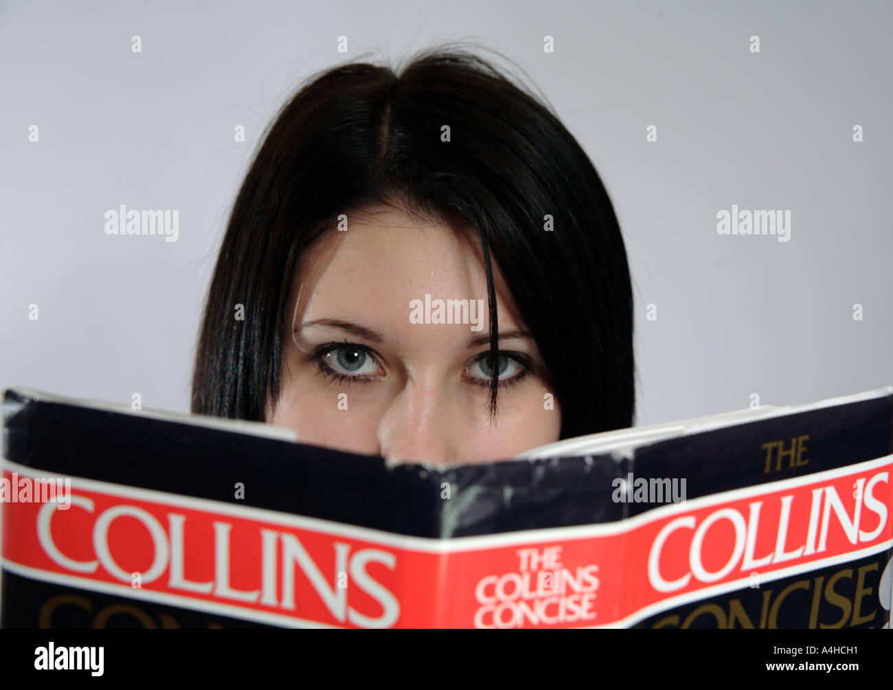 Young girl aged 16 reading a dictionary looking at the camera Stock ...