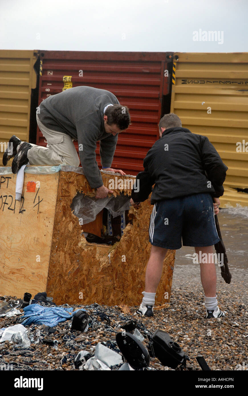 Men break open a crate washed up after the MSC Napoli cargo ship was ...