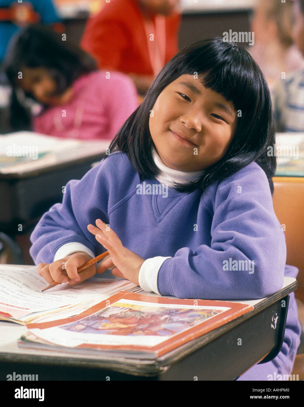Asian Girl looking up from her desk and smiling in Elementary School ...
