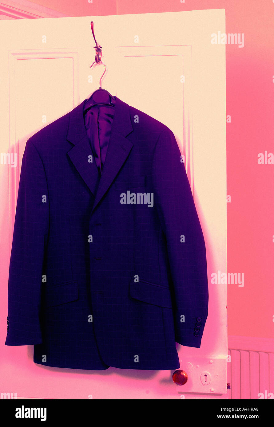Jacket hanging on hook on back of open door with plain wall to the ...
