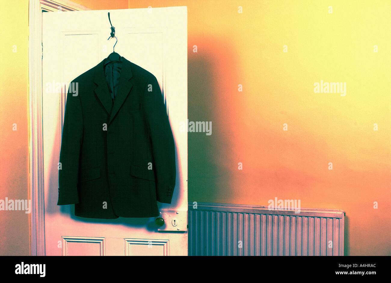 Jacket hanging on hook on back of open door with plain wall to the ...