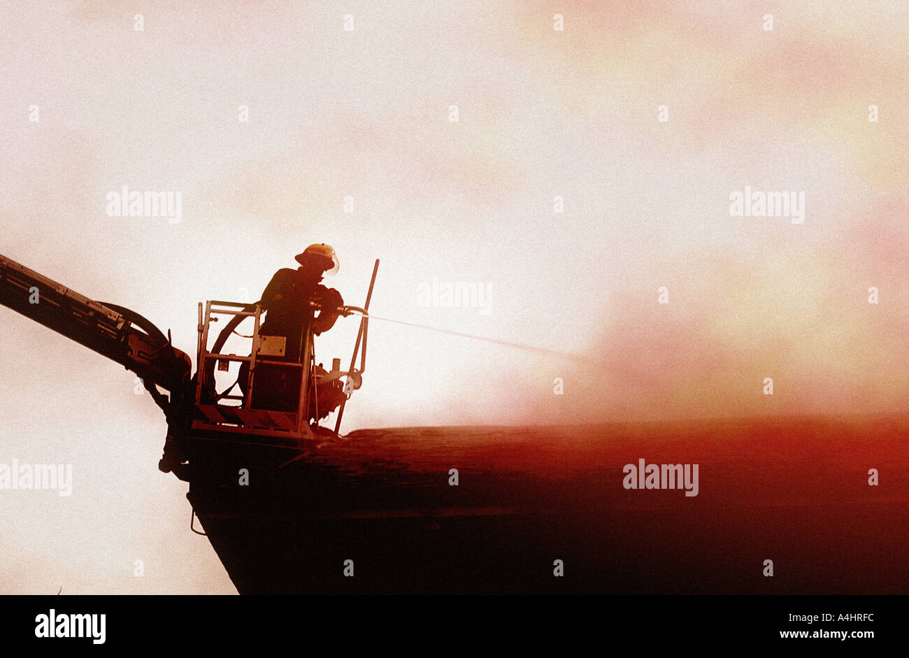 Fireman in cradle on cherry picker spraying fire in rooftop with water ...