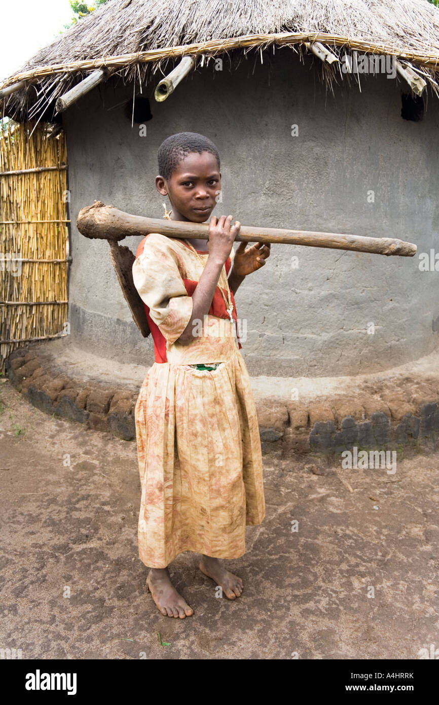 A young girl carrying a heavy mattock or Khasu (hoe) in the village of ...