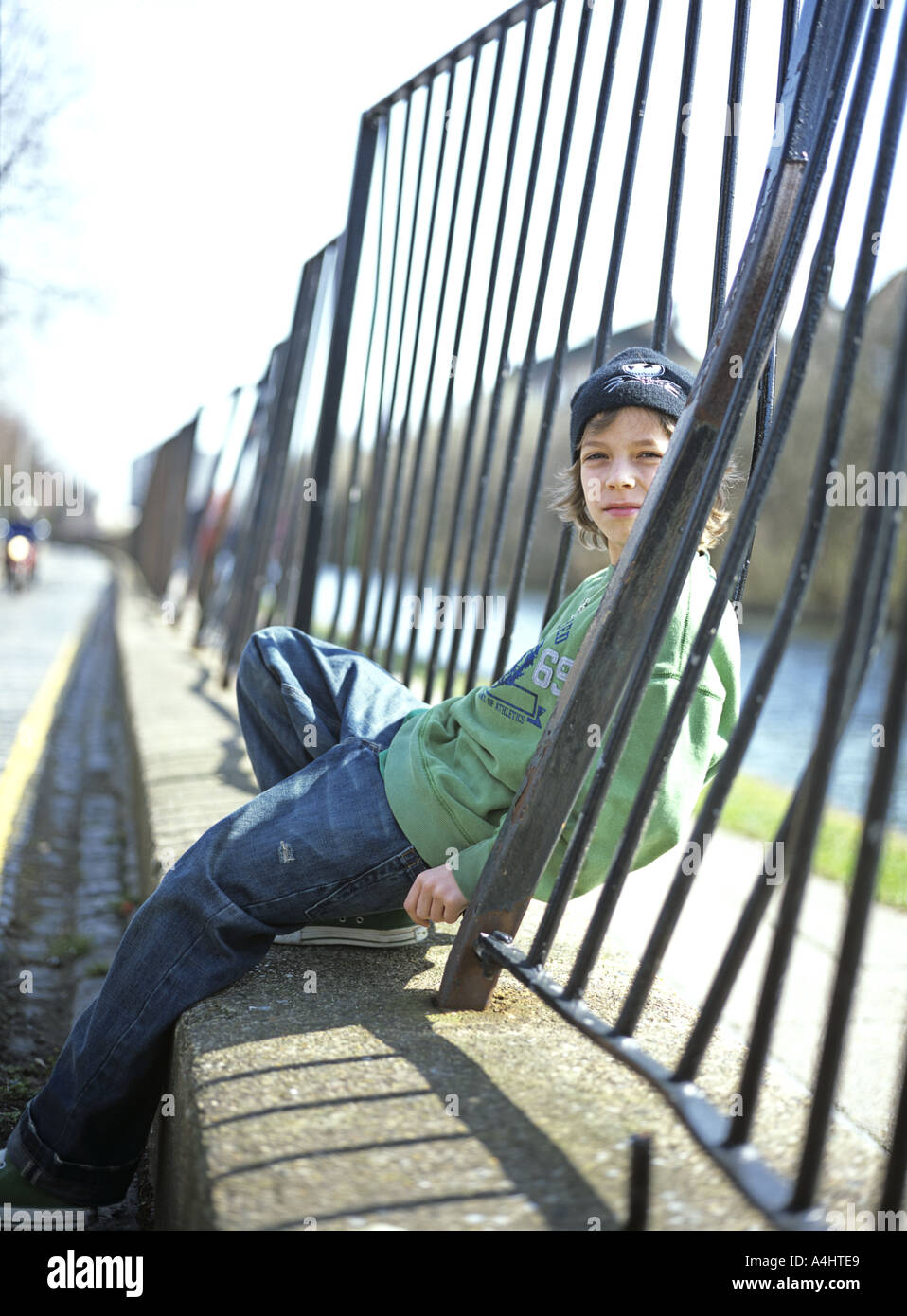 Boy lounging on bent railings Stock Photo - Alamy
